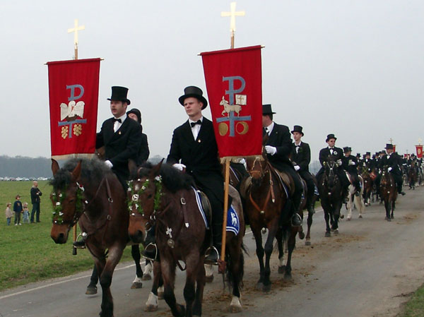 die ersten Reiter tragen die Kirchenfahnen